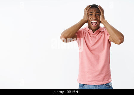 Shocked young man panicking, holding hands on head and staring ...