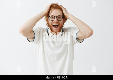 Impressed redhead man in glasses and t-shirt, checking out promo offer ...