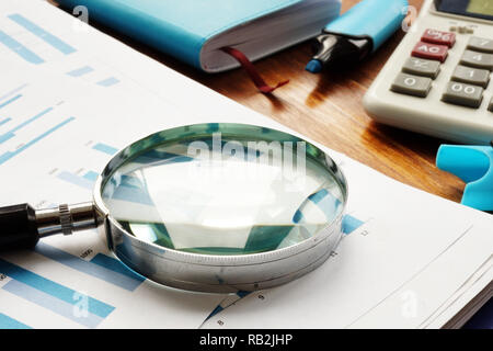 Auditing. Magnifying glass on financial documents with graphs. Audit ...