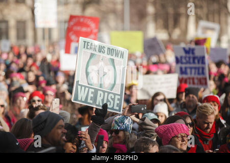 A group of protest signs rise above the crowd as thousands of ...