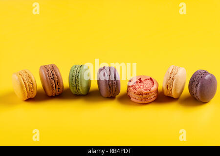 studio shoot of colorful macaroons line up curved on yellow background ...