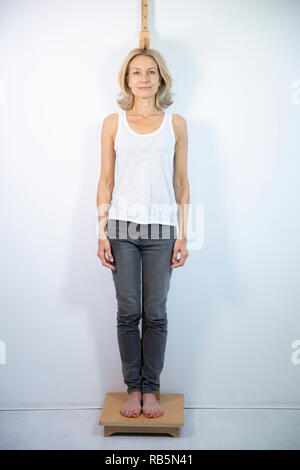 Woman measuring herself with a height measuring rod Stock Photo - Alamy