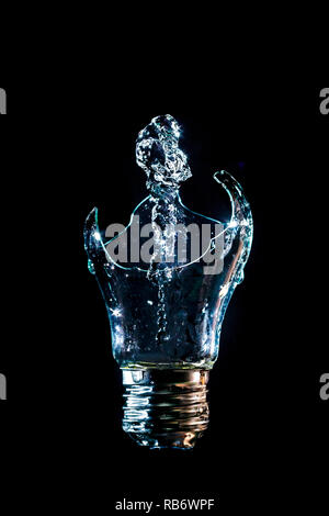 Creative broken light bulb with water fountain on isolated black ...