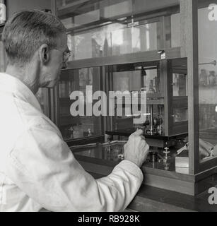 1950s, historical, male scientist in white coat at work in a chemical ...