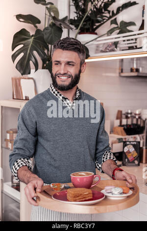 Cafeteria worker. Positive handsome bearded man wearing apron and ...