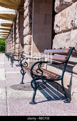 Outdoor street benches made of curved forged metal and wood standing in ...