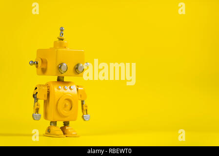 Cute, yellow, handmade robot on a white background with hard shadow ...