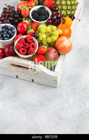 Wooden tray with fresh cherries, plums and apricots with water drops ...