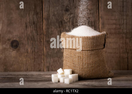 sugar falling in sack on wooden background Stock Photo - Alamy