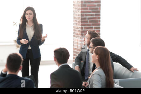 Five smiling employees sitting around their manager Stock Photo - Alamy