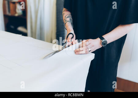 Female fashion designer cutting pattern at table in studio Stock Photo ...