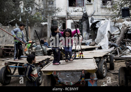 Palestinian refugee children seen playing on a cart in front of their ...