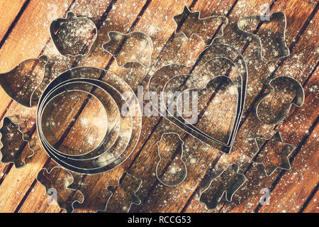 Different cutters for baking with flouring over brown wooden background ...