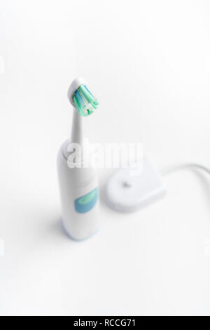 Electrical toothbrush near charger on white background, vertical shot ...