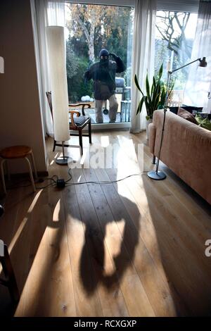Burglar planning burglary, spying out a house, symbolic image for ...