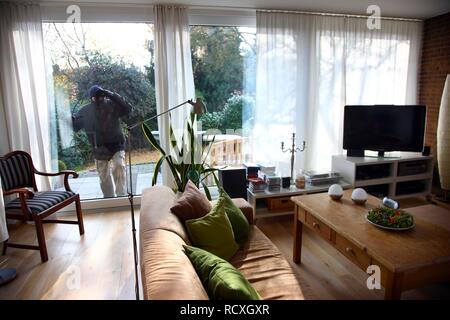 Burglar planning burglary, spying out a house, symbolic image for ...