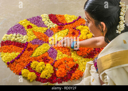 Woman lighting a lamp for a traditional Vishu kani (Vishukani) setting ...