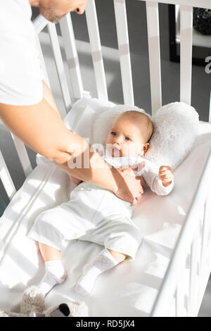 cropped view of father putting infant daughter into baby crib Stock ...