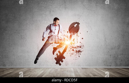 Determined businessman jumping and breaking with kick stone key figure ...