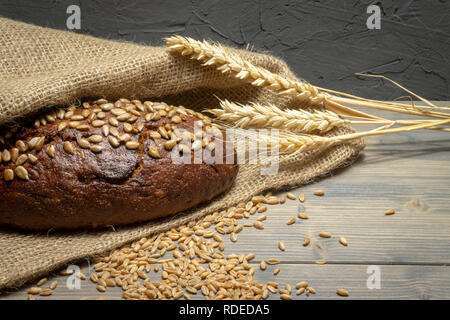 Bread with sunflowers seeds, ear of ripe wheat and sunflower blossom on ...