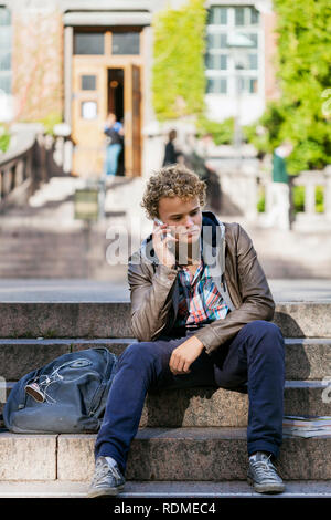 Young man sitting at a doorstep Stock Photo - Alamy