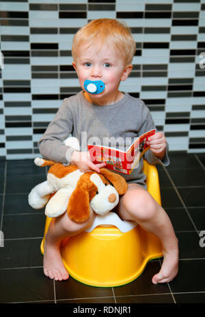 Boy sitting on potty and reading book at home Stock Photo - Alamy