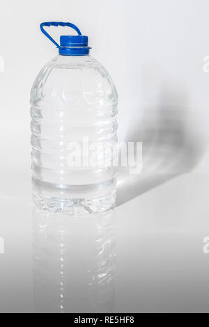 A five-liter plastic water bottle lies on a black wooden board, bottled ...