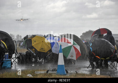 Wet aviation enthusiasts in the rain at an airshow as a RAF Nimrod jet ...