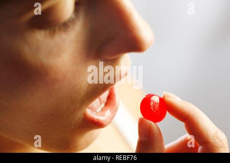 Woman taking a throat lozenge Stock Photo - Alamy