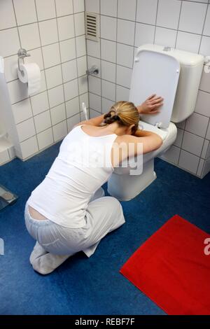 Woman is vomiting into a toilet bowl, nausea, sickness Stock Photo - Alamy