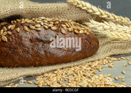 Bread with sunflowers seeds, ear of ripe wheat and sunflower blossom on ...