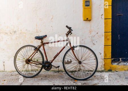 Old rustic vintage bicycle on the street near the color wall. Travel ...