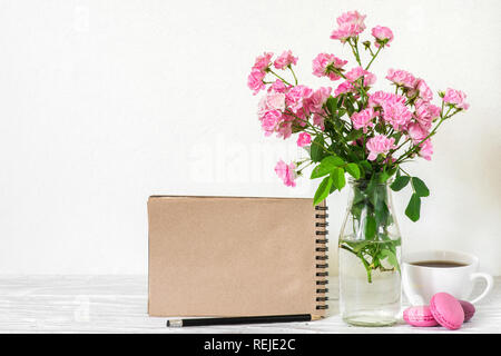 Bouquet of pink roses, coffee, blank paper and other objects on white ...