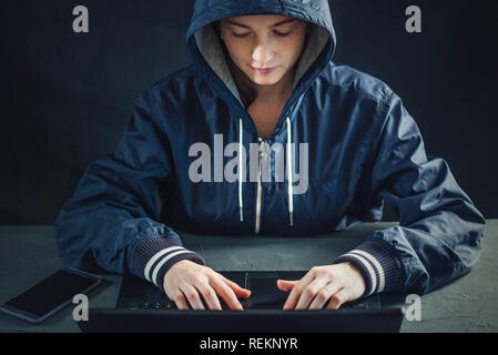 Hacker teen programmer uses a laptop to hack the system. Stealing ...