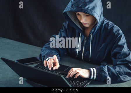 Hacker teen programmer uses a laptop to hack the system. Stealing ...