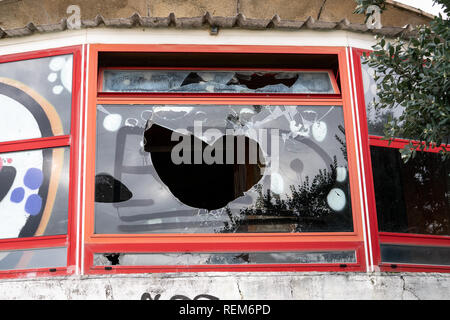 A vandalized house with broken window glass and spray painted graffiti ...