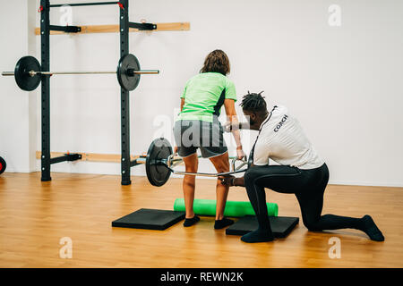 Black man coach training barbell with his patient in gym Stock Photo ...