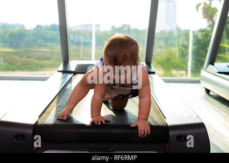 baby crawling on the treadmill in the gym with a view from the window ...