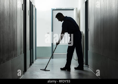 Man sweeping warehouse floor with broom Stock Photo - Alamy