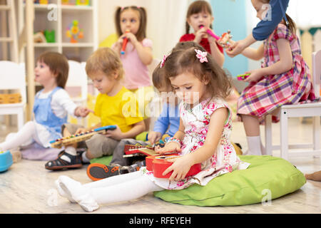 Kids learning musical instruments on lesson in kindergarten or ...