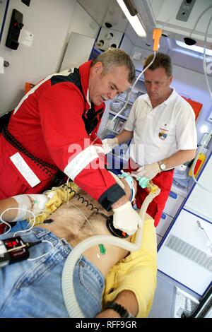 Cardiac patient in ambulance. Paramedics performing ECG on male vicitm ...