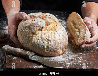 cook in a black tunic holds fresh baked bread, close up Stock Photo - Alamy