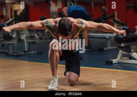 Very fit man with low body fat in the gym doing machine cable row ...