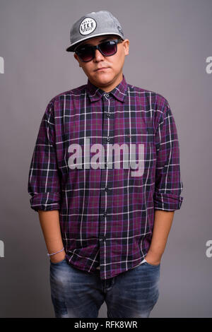 Young Asian gangster man against gray background Stock Photo - Alamy