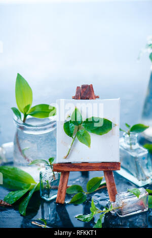 Artistic easel with a green leaf and glass jars with fresh plants ...