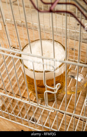 Glass of beer inside a cage, a concept on alcohol addiction and abuse ...