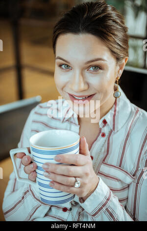 A beautiful pregnant Caucasian woman drinking tea while sitting on a ...