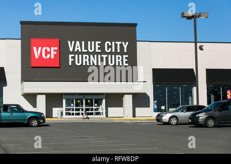 A logo sign outside of a Value City Furniture retail store location in ...
