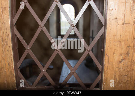 View through iron door with prison bars on male prisoner holding bars ...