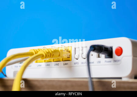 home wireless router with ethernet cables plugged in on blue background ...